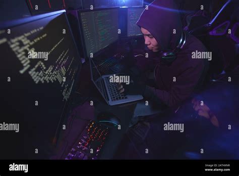 High Angle View At Asian Cyber Security Hacker Wearing Hood While Working On Programming In Dark