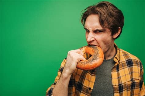 Premium Photo Young Man Bites Bagel
