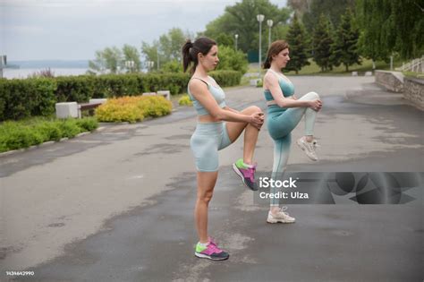 스포츠 복장을 한 스포티한 두 여자가 아침 운동을 하고 거리 운동장에서 스트레칭을 하고 있다 운동장에서 피트니스 운동 자연에서 인스 럭터와 함께 훈련 2명에 대한 스톡 사진