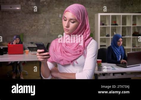 Nice Muslim Girl Wearing Pink Hijab Is Standing And Holding Her