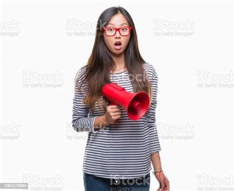 젊은 아시아 여 자가 깜짝 얼굴 두려워 하 고 공포 식으로 흥분 충격에서 무서 워 격리 된 배경 위에 확성기를 들고 감정에 대한