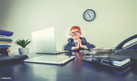 책상에서 노트북 컴퓨터로 작업하는 어린 소년의 유머러스한 이미지 그는 양복을 입고 행복한 미소를 짓고 있습니다 It 지원에 대한 스톡 사진 및 기타 이미지 Istock