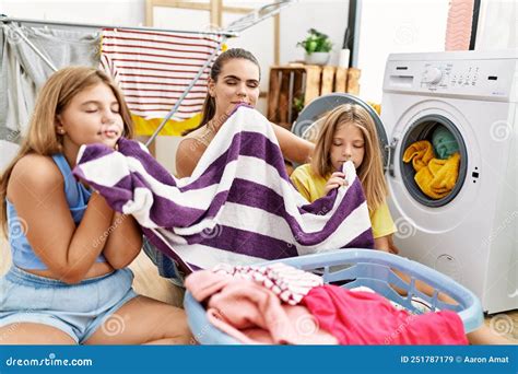 Mother And Daughters Washing Clothes Smelling Towel At Laundry Room