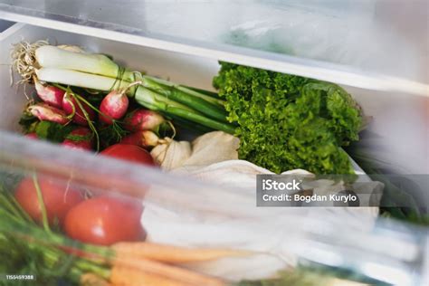 냉장고에 열려있는 서랍에 신선한 야채 플라스틱 무료 당근 토마토 버섯 양파 무 샐러드 및 냉장고 시장에서 Arugula 제로 폐기물 식료품 쇼핑 개념입니다 재사용 가능한