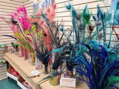 Colorful Dyed Peacock Feathers In Glass Vases On Tabletop Editorial
