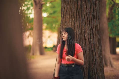 Shot Of A Beautiful Young Woman Standing Behind A Tree In A Forest