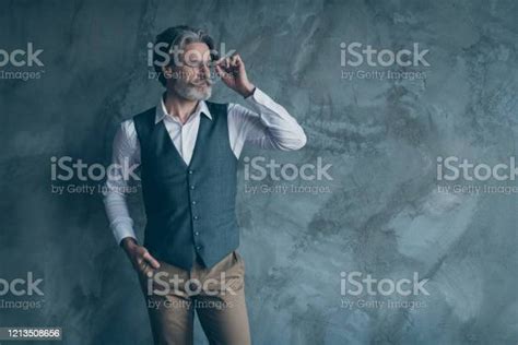 초상화 의 Virile 신사 노인 봐 복사 공간 꿈 같은 터치 손 안경 착용 갈색 바지 의상 콘크리트 벽 회색 색상 배경 위에