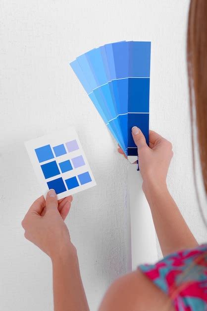 Premium Photo Woman Choosing Color For Wall From Swatches In Room