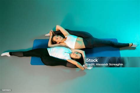 네온 불빛에 피트 니스 매트에 바닥에 스트레칭 스포츠 의류에 아름 다운 두 젊은 슬림 체조 여자 체조 운동을 하 고 유연한 근육 여성 2명에 대한 스톡 사진 및 기타 이미지