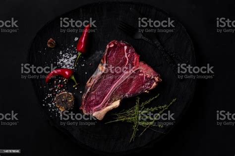 검은 나무 조각과 어두운 배경에 칼과 포크로 로즈마리 소금 마늘 고추 후추로 뼈에 쇠고기 수평 방향 가지 채소에 대한 스톡 사진