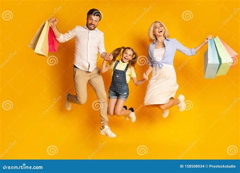 Familia Feliz Saltando Con Bolsas De Compras Sobre Fondo Amarillo Foto