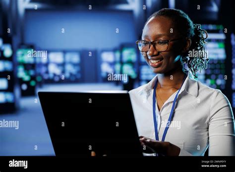 African American Woman Between Server Farm Rows Providing Processing