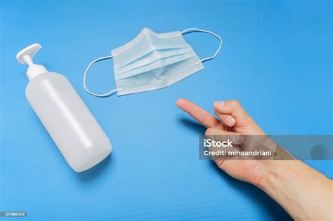 손 소독제 얼굴 마스크와 손을 파란색 배경에 가운데 손가락을 보여주는 선택적 초점 코로나바이러스 전염병의 끝 성공 바이러스 근절