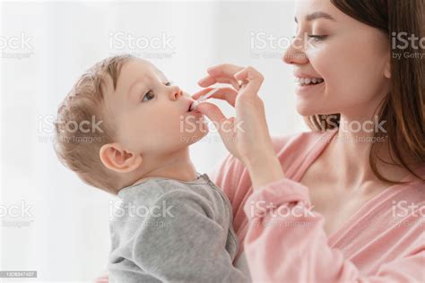 행복한 백인 어머니는 이가 나는 복통을 위한 약으로 그녀의 작은 딸 아들 아이 아이를 먹이 의료 및 보육 모성 개념 아기에 대한