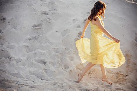 아름 다운 Boho 소녀 호수 근처 일몰 빛 모래 해변에 산책 휴식 재미와 실행 바람 머리와 노란색 드레스를 입고 매력적인 젊은