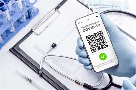 코로나바이러스 여권 의사가 들고 있습니다 병원 백색 배경에 의사 청진기 주사기 및 의료 장비와 스마트 폰 화면에 코비드 예방 접종 증명서 또는 백신 여권 Brand Name
