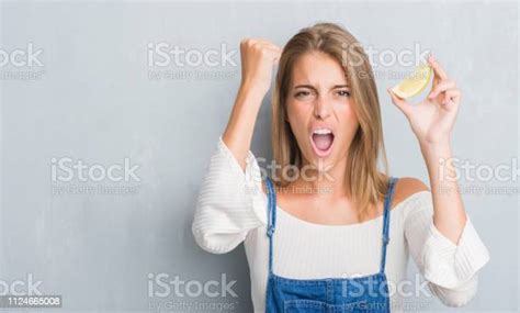 그런 지 회색에 아름 다운 젊은 여 자가 벽 레몬 슬라이스 짜증과 분노 미친 제기 손으로 소리와 좌절 외치고 분노 개념 감정에