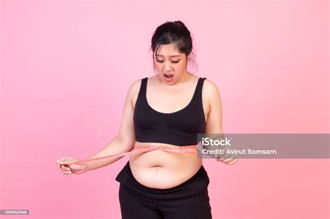 몸을 가진 뚱뚱한 여자는 고립된 분홍색 배경을 측정합니다 그녀의 배꼽 지방을 측정 과체중 여성 뚱뚱한 여자는 분홍색 배경위에 그녀의 위를 측정합니다 체지방 과체중을 가진