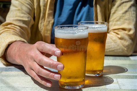 Men With Two Glasses Of Fresh Cold Lager Beer In French Outdoor Cafe