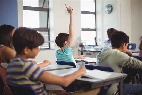学校孩子们在教室里举手认真听讲的同学