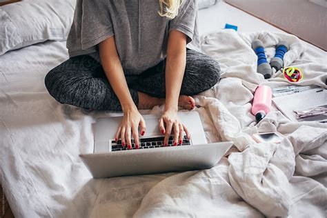 Blonde Woman Sitting On The Bed And Working On Her Laptop By Stocksy