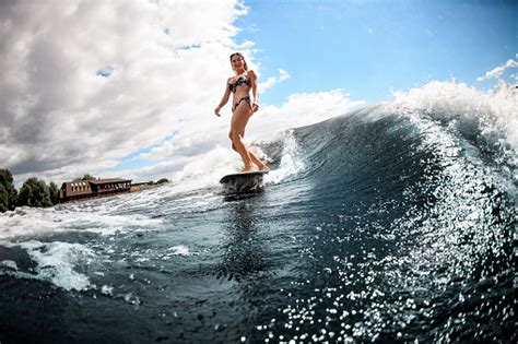 수영복을 입은 아름다운 여성이 서핑보드에 서서 파도를 타고 있습니다 강에 대한 스톡 사진 및 기타 이미지 강 강둑 관능 Istock