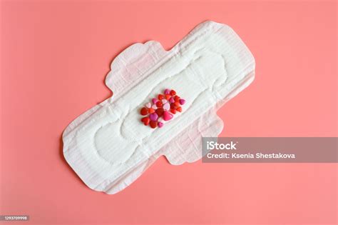 분홍색 배경에 혈액을 모방로 마음의 모양에 빨간색과 분홍색 구슬과 분비의 정상적인 풍부에 대한 여성의 생리 위생 패드 또는 냅킨