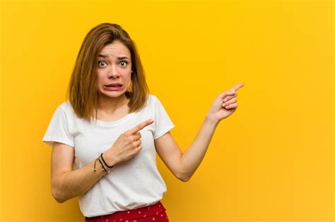 Premium Photo Young Woman Shocked Pointing With Index Fingers