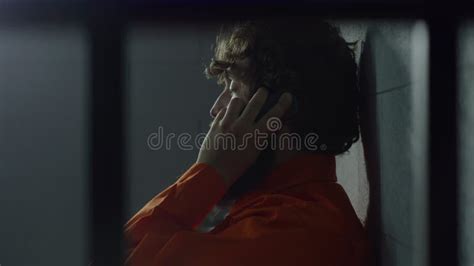 Prisoner In Orange Uniform Talks On Phone In Prison Cell Stock Video