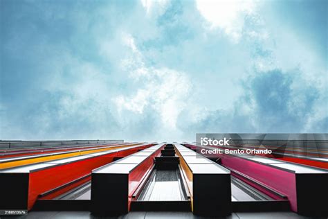 구름 낀 하늘을 배경으로 생생한 수직 패널이 있는 현대 건물 외관의 추상적 전망 도시 건축 창의성 및 대담한 디자인을 독특한 관점과 생생한 색상으로 포착합니다 0명에 대한