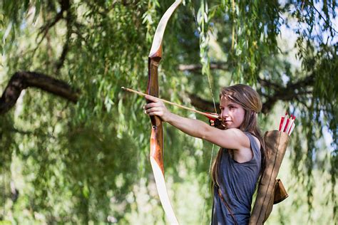 Young Woman Aiming Bow And Arrow In The Nature By Stocksy Contributor