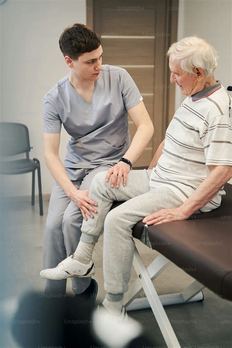 정형외과 의사가 노화된 남자의 오른쪽 다리에 손을 얹고 상태를 검사하고 환자의 얼굴을 보고 있다 사진 Unsplash의 사람 이미지