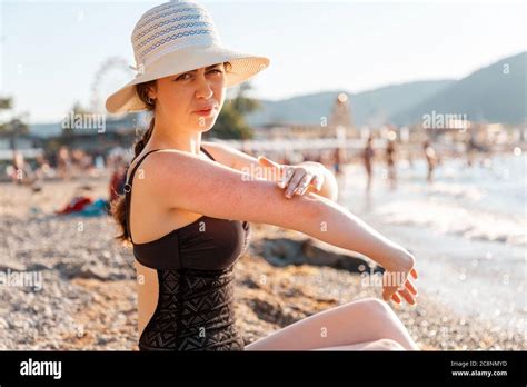 Une Femme En Maillot De Bain Est Assise Sur La Plage Et Irrite Sa Main Avec Des Rougeurs Et Une