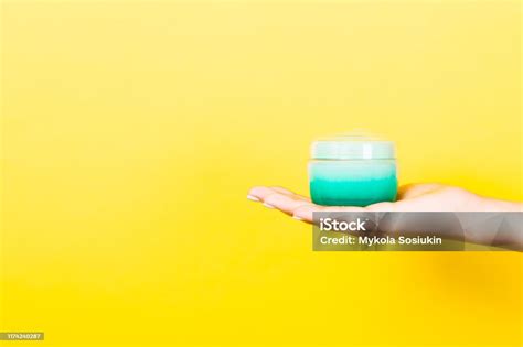여성 손 들고 크림 병 의 로션 분리 소녀는 노란색 배경에 항아리 화장품을 제공합니다 개념에 대한 스톡 사진 및 기타 이미지