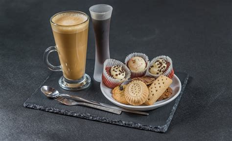 오른쪽 은 세 버터 머핀과 흰색 접시에 쁘띠 포와 향기로운 커피 라떼에 오른쪽 보기 유리 숟가락과 포크에 커피 리큐어 검은 돌 접시에 전체 0명에 대한 스톡 사진 및 기타