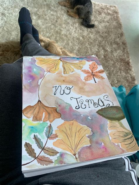 A Person Holding A Book With Leaves On It
