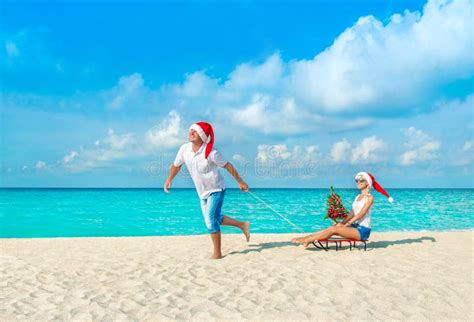 Молодые пары бежать на море пляж в шляпах Santa с скелетоном и Ch