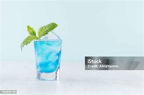 얼음 조각이 있는 블루 큐라소 칵테일 화이트 우드 보드의 고급 샷 글래스의 그린 민트 파스텔 민트 컬러 월 0명에 대한 스톡 사진 및 기타 이미지 Istock
