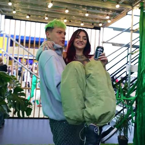 A Man And Woman Standing Next To Each Other In Front Of Some Stairs