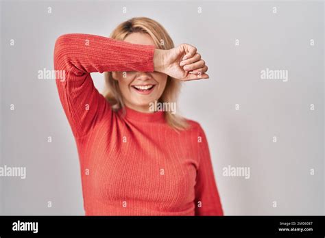 Blonde Woman Standing Over Isolated Background Covering Eyes With Arm