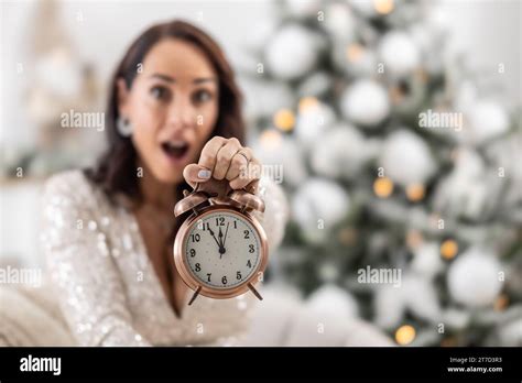 Surprised Facial Expression Of A Woman Next To A Christmas Tree Showing Alarm Clock With Five