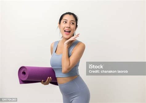고립 된 흰색 배경에 요가 매트를 들고 운동복을 입은 젊은 아름다운 아시아 여성 초상화 스포티 한 여자는 스튜디오에서 운동
