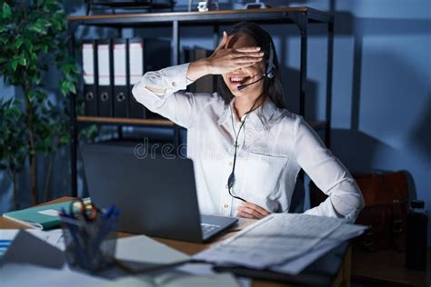 Young Brunette Woman Wearing Call Center Agent Headset Working Late At Night Smiling And