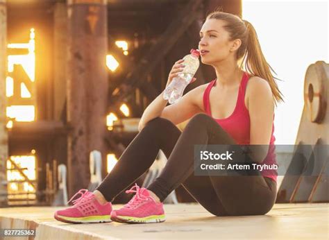 물 균형을 유지입니다 가로 샷 스포츠에 아름 다운 젊은 여자의 다리에 앉아있는 동안 조깅 후 멀리 보고와 식 수를 착용 하십시오