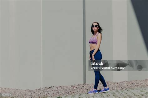 스포츠 복에서 활동적인 적합 여성의 수평 샷은 자신있게 거리로 보인다 그늘을 착용 좋은 야외 운동 후 휴식 그녀의 건강과 그림의