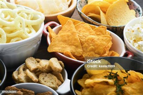 건강에 해로운 음식이나 간식 땅콩 팝콘 양파 반지와 소금에 절인 프레첼을 오래된 나무 배경의 그릇 접시에 담은 모든 고전적인 감자 스낵 인물 심장 피부 치아에 대한 건강에