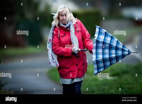 Woman In A Red Coat With A Blue Umbrella On A Windy Stormy Day Uk