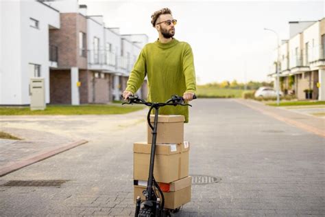 Premium Photo Man Drives Electric Scooter With Cardboard Packages