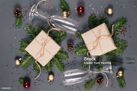 크리스마스 휴일 구성 전나무 나뭇 가지의 공예 종이 두 개의 안경 샴페인 소나무와 색종이 회색 배경에 장식 된 수제 선물 상자