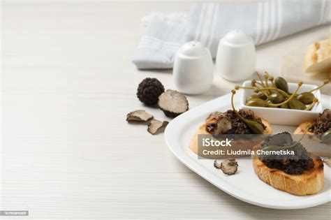 흰 나무 테이블에 트뤼플 소스와 카퍼 베리를 곁들인 맛있는 브루 쉐타 텍스트를 위한 공간 브루스케타에 대한 스톡 사진 및 기타